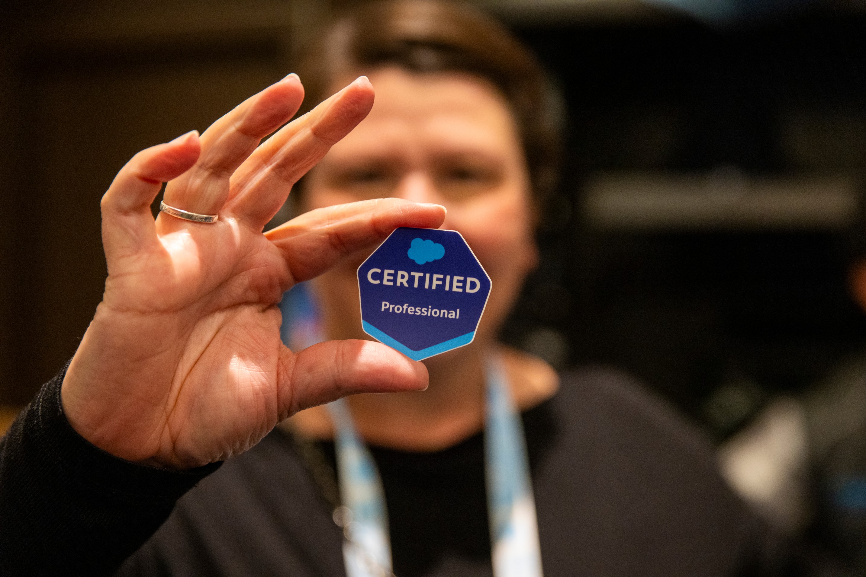 Out-of-focus person holding up an in-focus Salesforce Certified ...